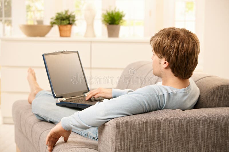 Man with laptop on couch stock image. Image of domestic - 16418779