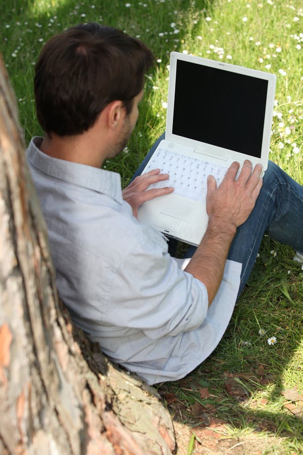 Man with laptop under tree stock photo. Image of black - 26505194