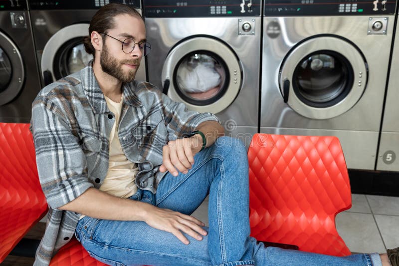 Man in Laundromat Using Washing Machine and Looking at His Smartwatch ...