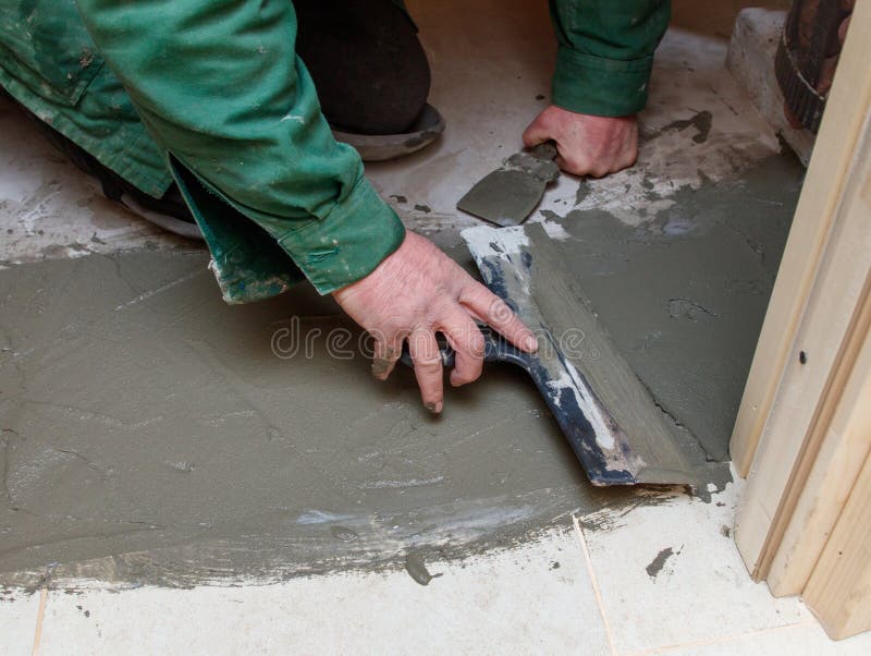 A Man is Laying Down and Using a Trowel To Spread Cement Stock Photo ...