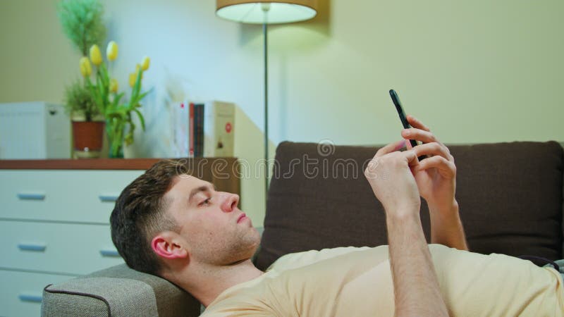 Man Laying on the Sofa and Using Mobile Phone Stock Photo - Image of ...