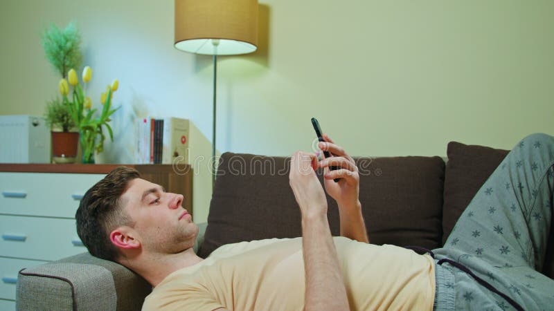 Man Laying on the Sofa and Using Mobile Phone Stock Image - Image of ...