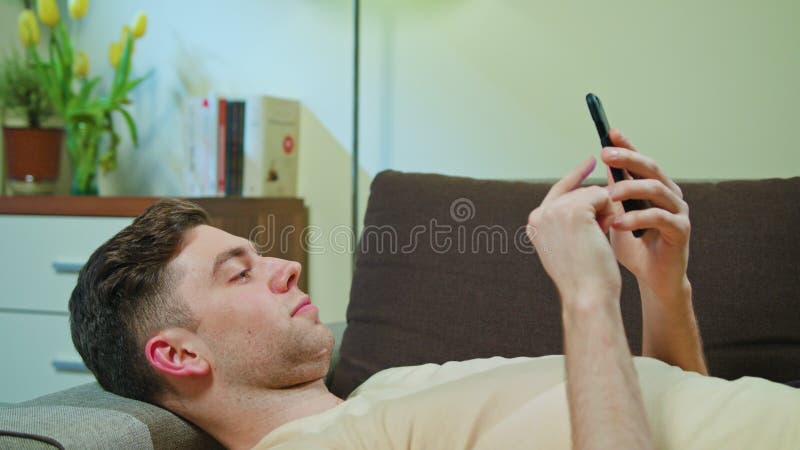Man Laying on the Sofa and Using Mobile Phone Stock Image - Image of ...