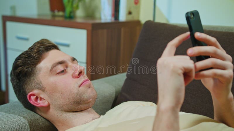 Man Laying on the Sofa and Using Mobile Phone Stock Image - Image of ...