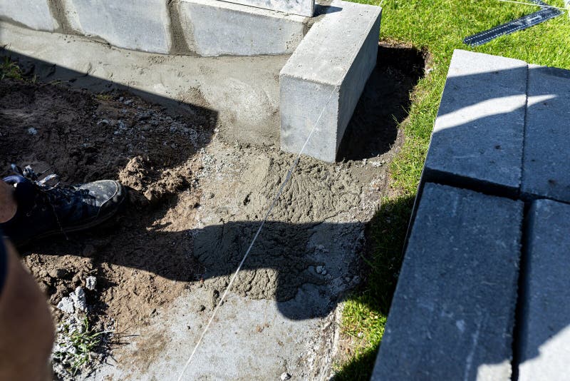 A Man Lays Concrete Blocks on a Poured Foundation, Gluing Them with ...