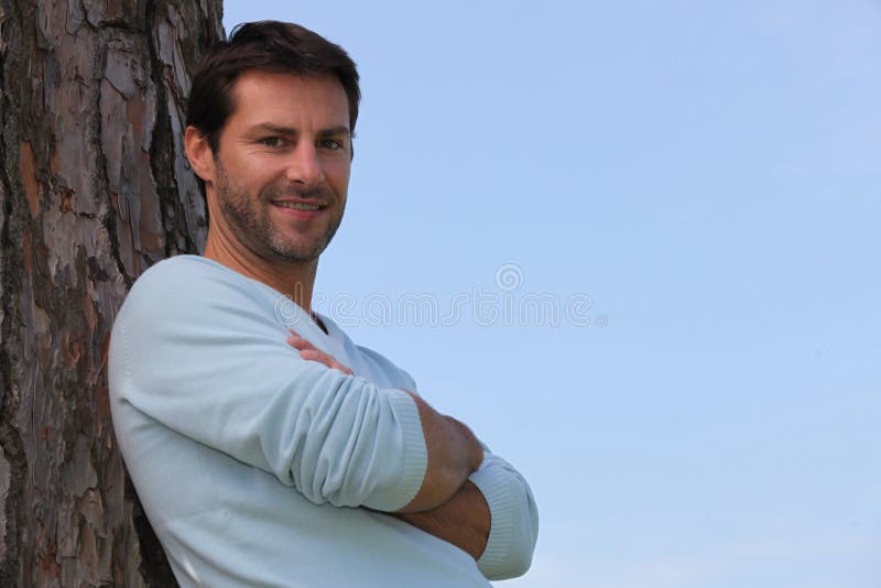 Man leaning against a tree stock photo. Image of front - 25357730