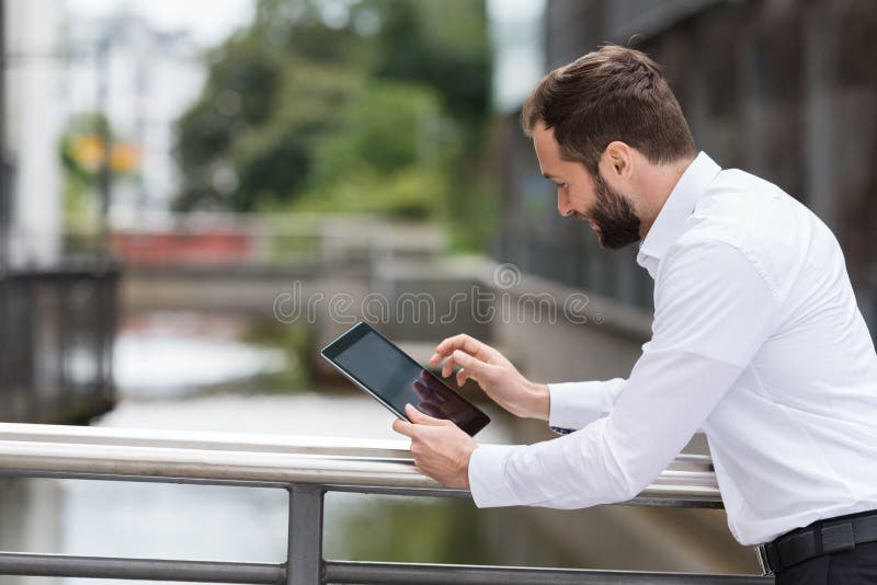 Man Leaning on a Bridge Working on a Tablet Stock Photo - Image of ...