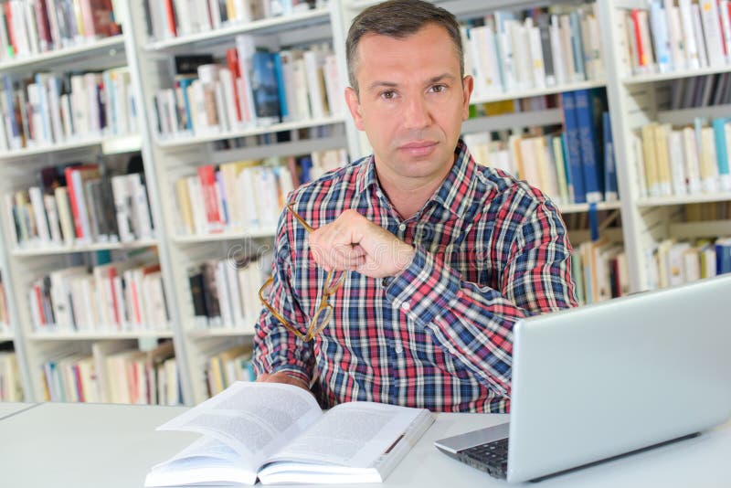 Man in Library with Book and Laptop Stock Image - Image of bookshelves ...