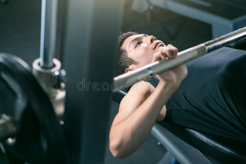 Man Lifting Dumbbell Weights while Lying Down in Gym. Stock Photo ...