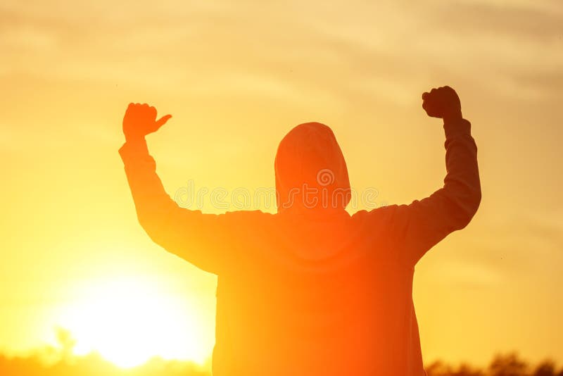 A Man in the Light of the Sunset with His Hands Up, the Concept of ...