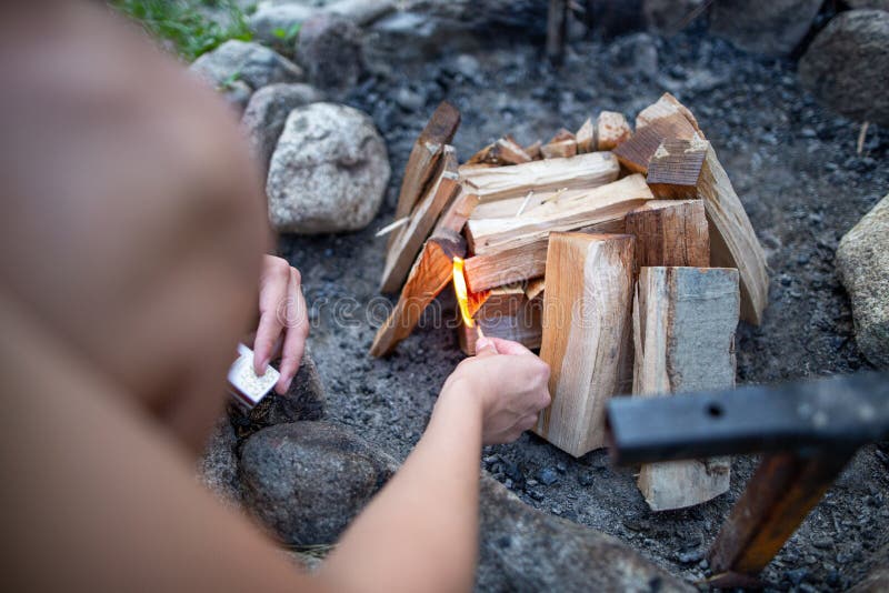 Man Lighting a Stack of Firewood with a Match in a Fire Pit Stock Photo ...