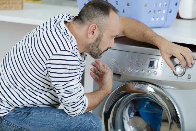 Man Loading Clothes into Washing Machine in Kitchen Stock Image - Image ...