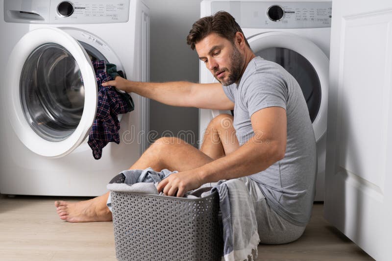 Man Loading Clothes into Washing Machine in Laundry Room. Middle Age ...