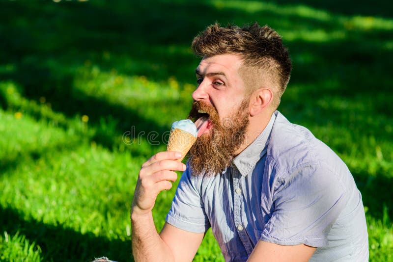 Man With Long Beard Eats Ice Cream While Sits On Grass Bearded Man