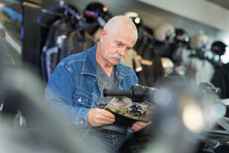 Man Looking at Brochure in Motorcycle Showroom Stock Photo - Image of ...
