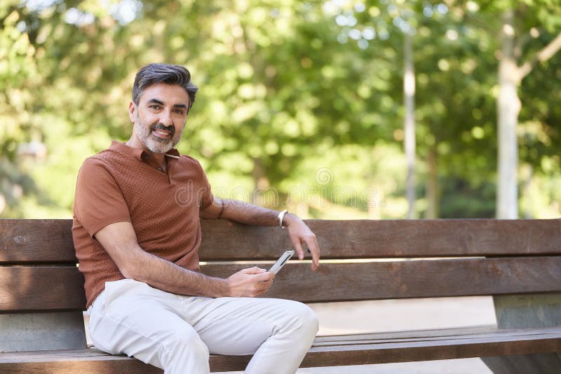 Man Looking at the Camera and Smiling while Holding a Mobile Phone ...