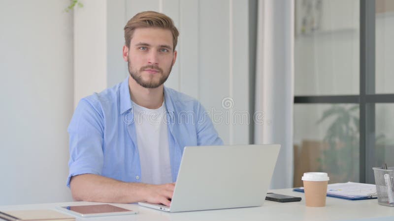 Man Looking at Camera while Using Laptop in Office Stock Image - Image ...
