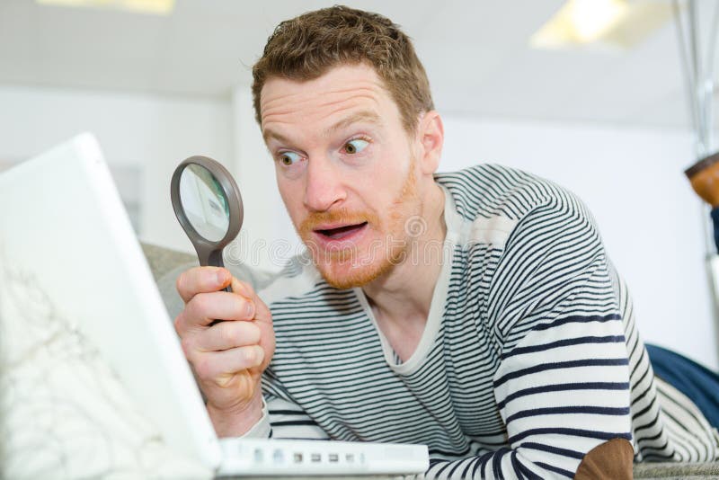 Man Looking Excitedly through Magnifying Glass at Laptop Screen Stock ...