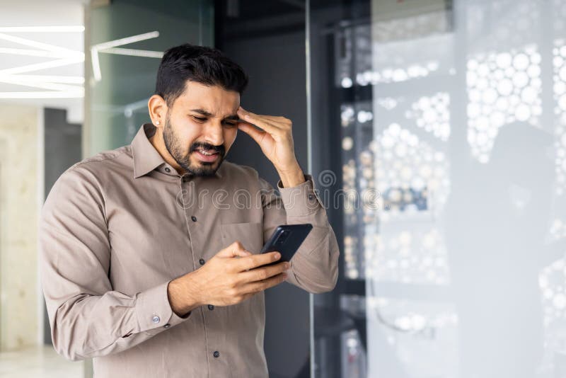 A Man is Looking at His Cell Phone with a Concerned Expression on His ...