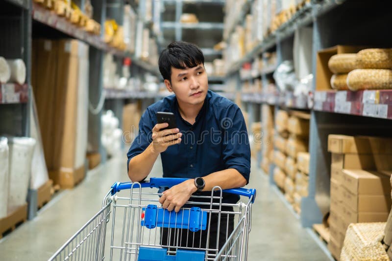 Man Looking at His Mobile Phone and Shopping in Warehouse Store Stock ...