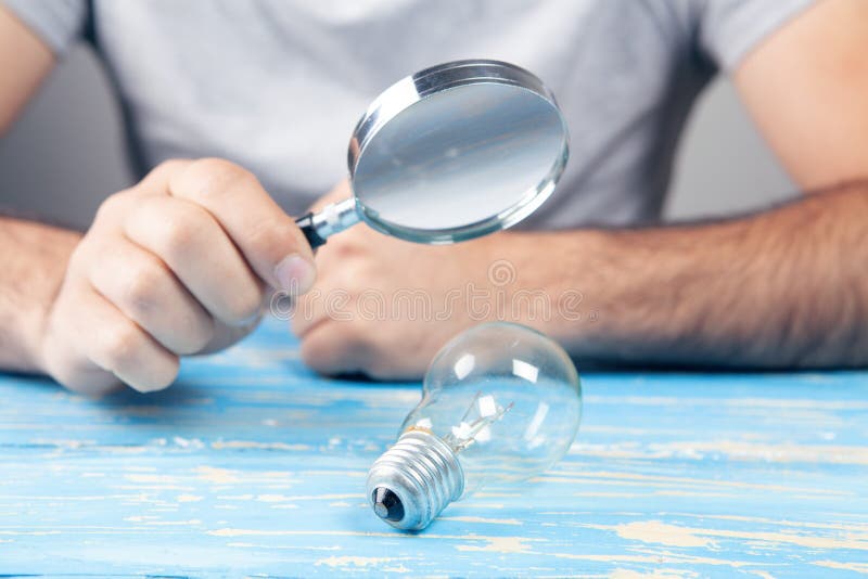 A Man Looking at a Light Bulb with a Magnifying Glass Stock Image ...