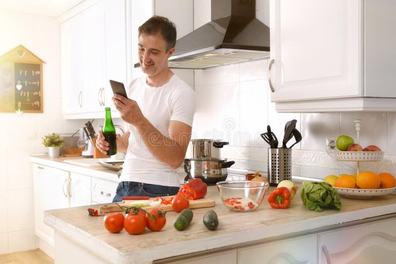 Man Looking at Mobile Phone with Beer while Cooking Stock Image - Image ...