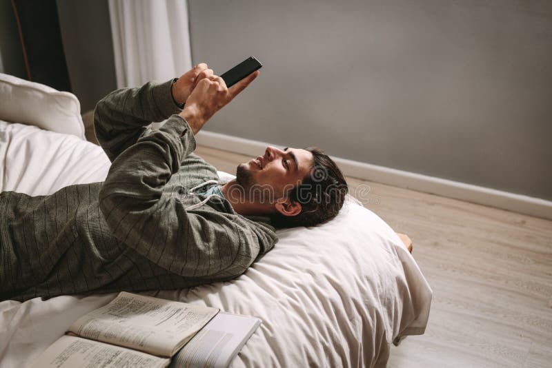 Man Looking at Mobile Phone Lying on Bed Stock Image - Image of ...