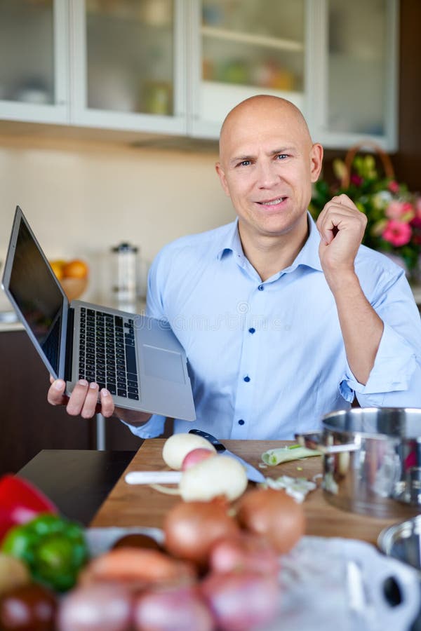 Man Looking at Recipe in Laptop while Cooking Dinner. Stock Photo ...