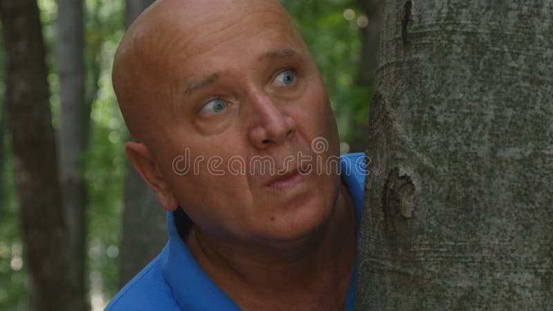 Man Looking Scared with Terrified Eyes is Hiding after a Tree in the ...