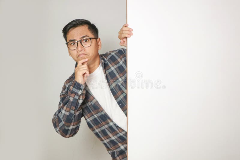A Man Looking Something from Behind White Wall with Confused Expression ...