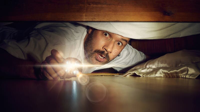 Man Looking Under Bed with Flashlight. Shocked, Excited and Scared Face ...