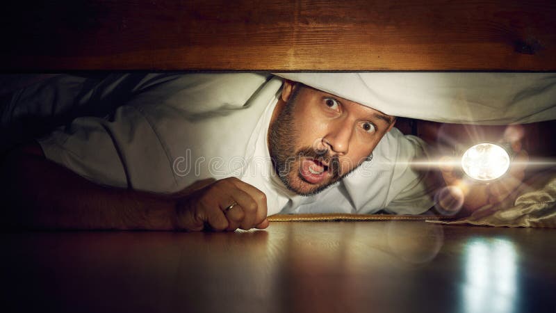 Man Looking Under Bed with Flashlight. Shocked, Excited and Scared Face ...