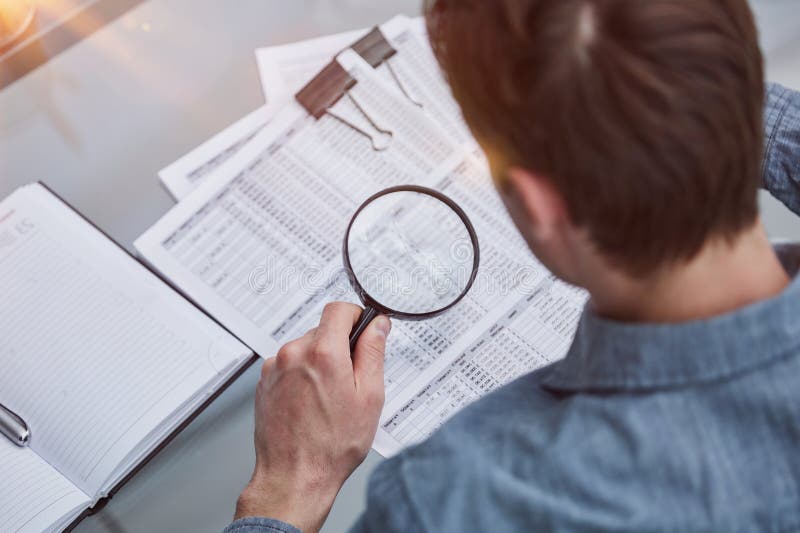 Businessman Looking through a Magnifying Glass To Documents Note in the ...