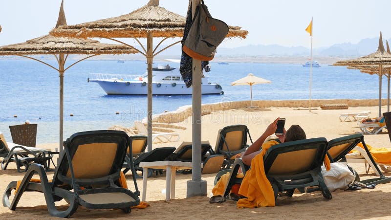 Man is Lying on the Beach Couch Under the Umbrella Stock Photo - Image ... Man is Lying on the Beach Couch Under the Umbrella Stock Photo - Image ...