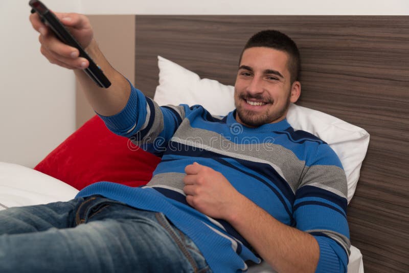 Man Lying on Bed and Holding Remote Control Stock Image - Image of ...