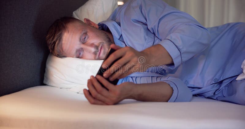 Man Lying on Bed Using Mobile Phone Stock Photo - Image of watching ...