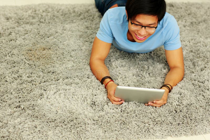 Man Lying on the Carpet with Tablet Computer Stock Photo - Image of ...