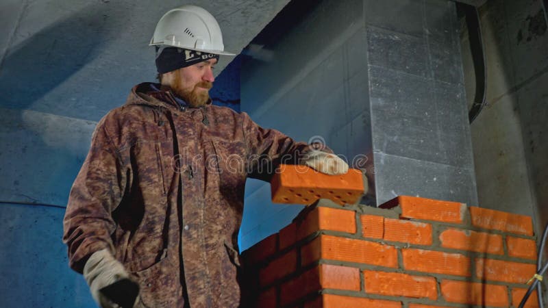 Man Makes Brickwork at Construction Site. Clip. Uniformed Worker Makes ...
