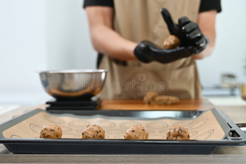 A Man is Making Cookies and Wearing Gloves. he is Using a Scale To ...
