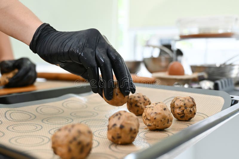 A Man is Making Cookies and Wearing Gloves. he is Using a Scale To ...