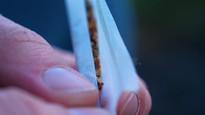 Man Making Joint and a Stash of Marijuana Outside. Concept of: Smoke ...