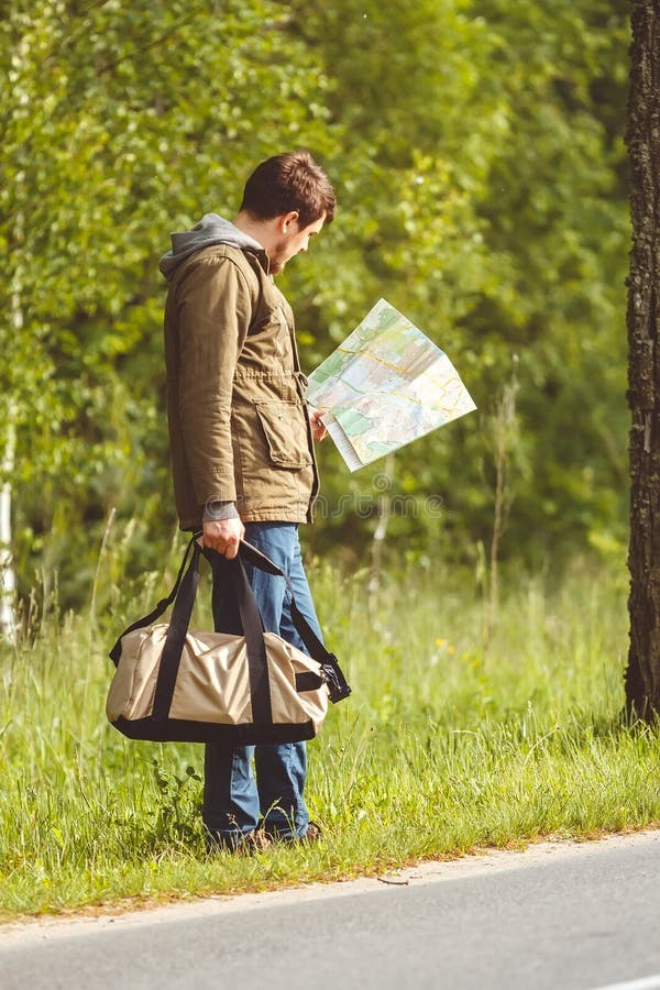 Man with Map and Bag in Hand Walking on a Roadside Stock Photo - Image ...
