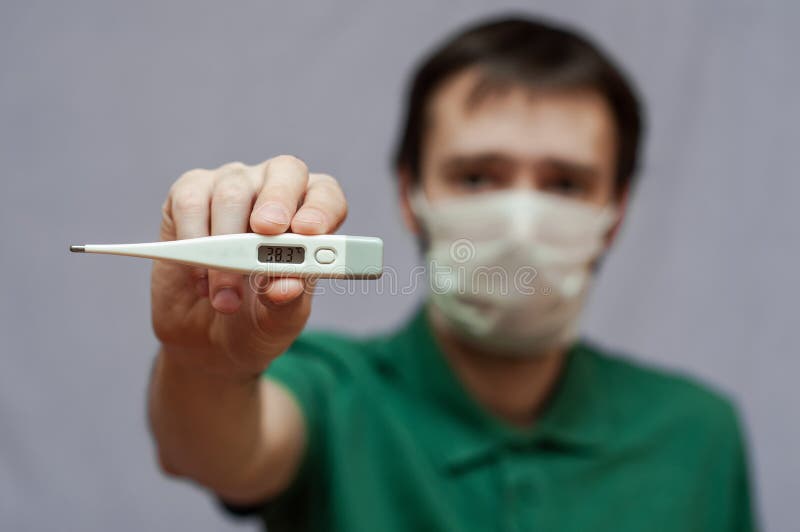 Man in Mask with an Electronic Thermometer with a High Temperature in ...