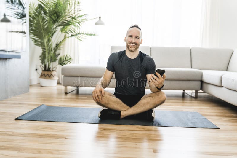 Man on a Mat Doing Some Exercise at Home Using Cellphone To Help ...