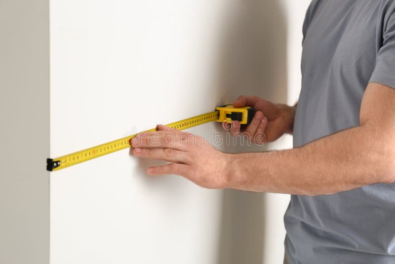 Man Measuring White Wall Indoors. Construction Tool Stock Image - Image ...