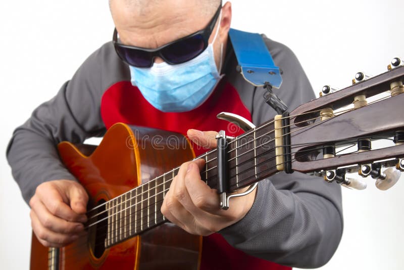 Man in a Medical Mask Plays the Classical Guitar on a White Background ...