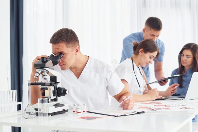 Man with Microscope. Group of Young Doctors is Working Together in the ...