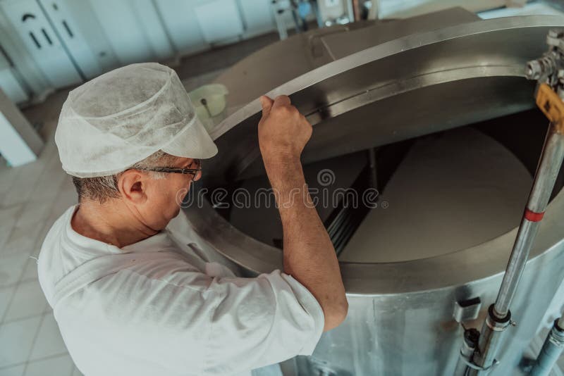 Man Mixing Milk in the Stainless Tank during the Fermentation Process ...