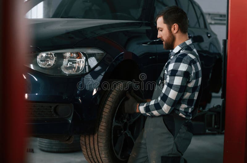 Man is Moving the Wheel. Employee is Working in the Auto Salon Stock ...