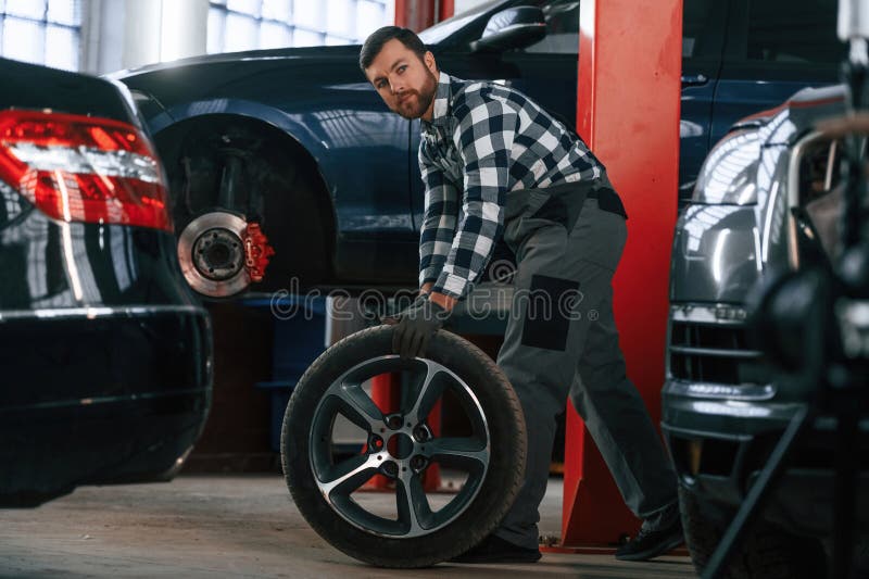 Man is Moving the Wheel. Employee is Working in the Auto Salon Stock ...